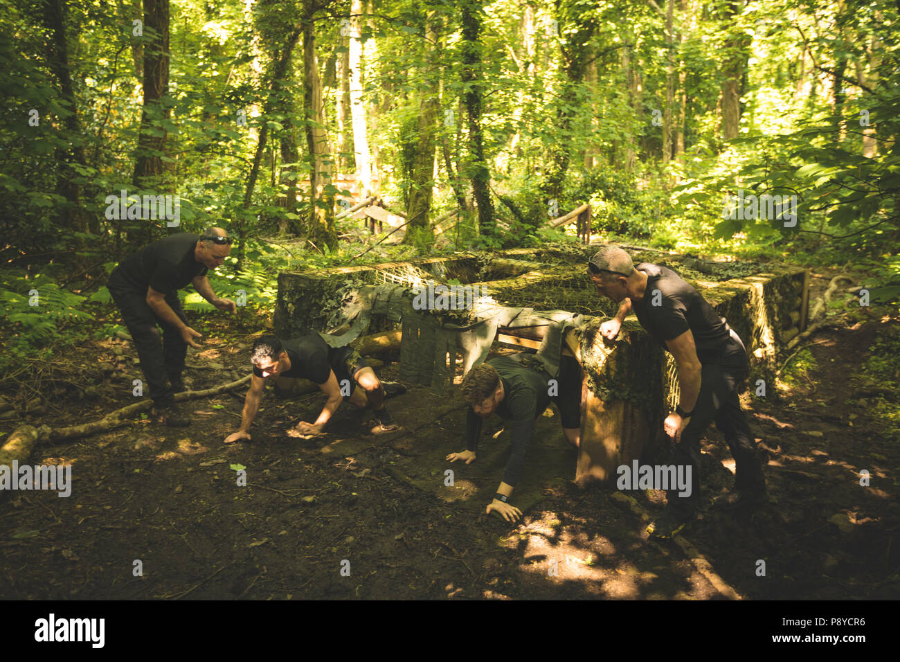 Fit men crawling under the net during obstacle course Stock Photo - Alamy