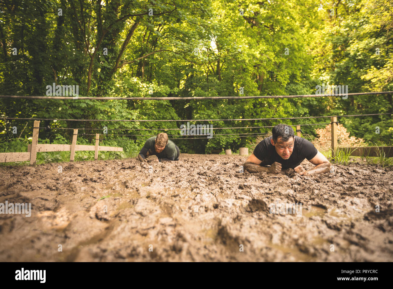 Fit men training under obstacle course Stock Photo - Alamy