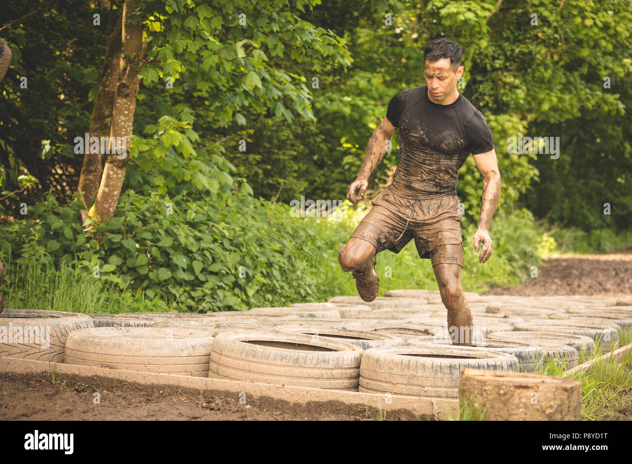 Fit man training over tyres obstacle course Stock Photo - Alamy