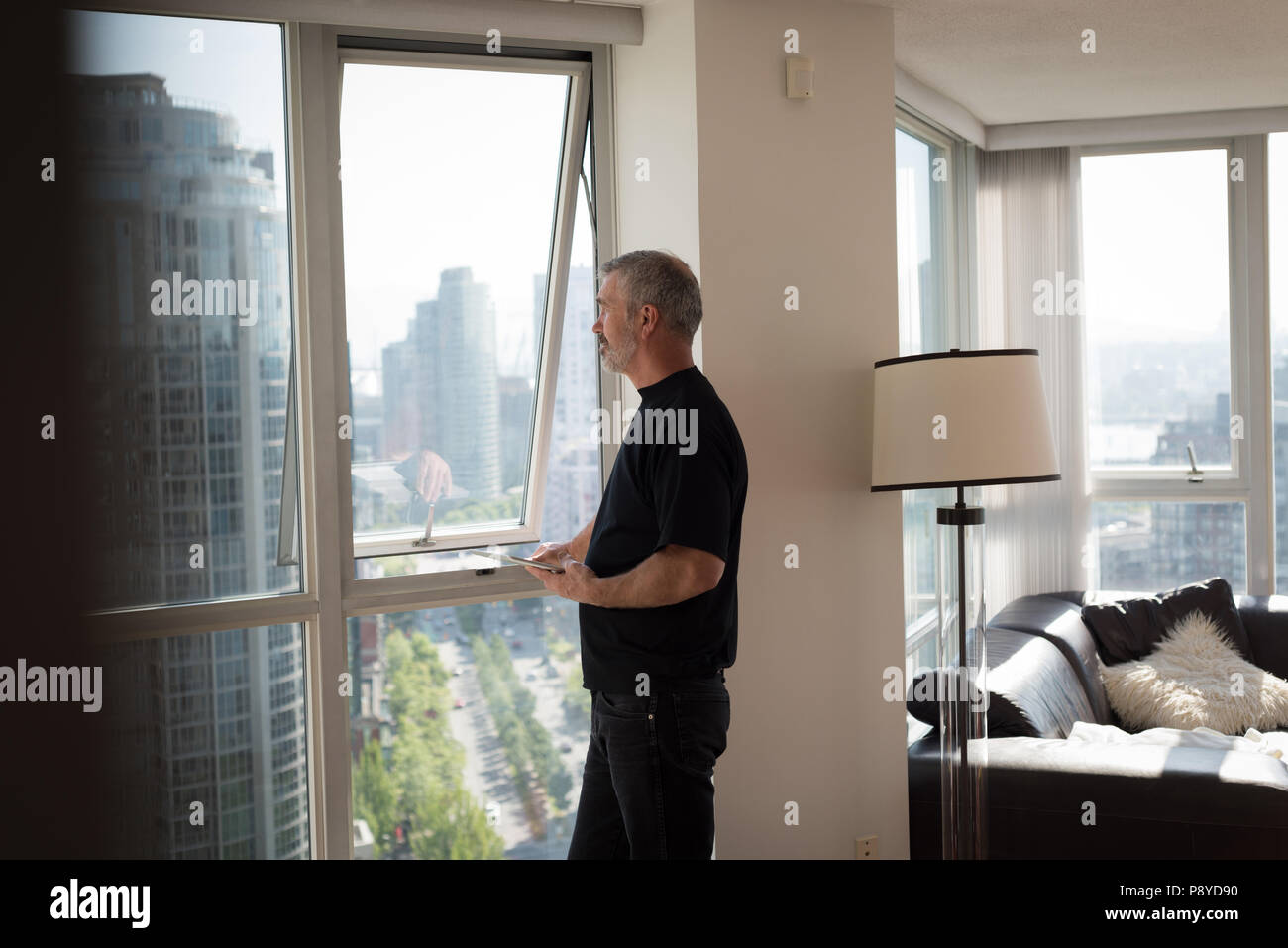 Man looking through the window at home Stock Photo - Alamy