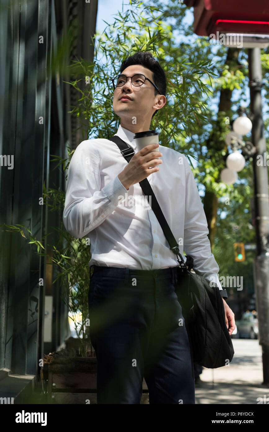 Man with coffee cup looking at a building Stock Photo - Alamy