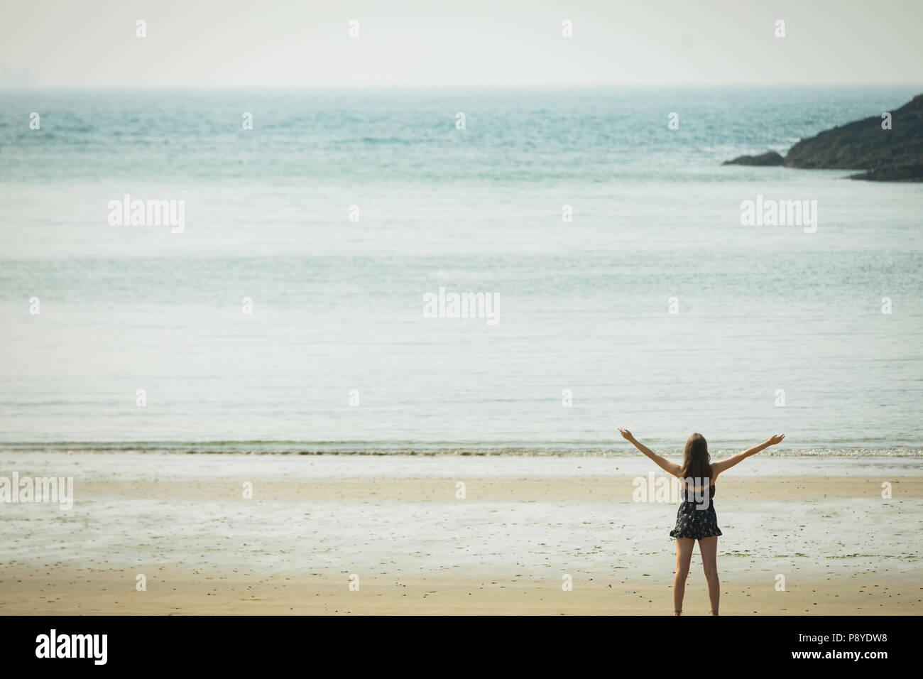Woman standing on the beach with her hands spread Stock Photo - Alamy