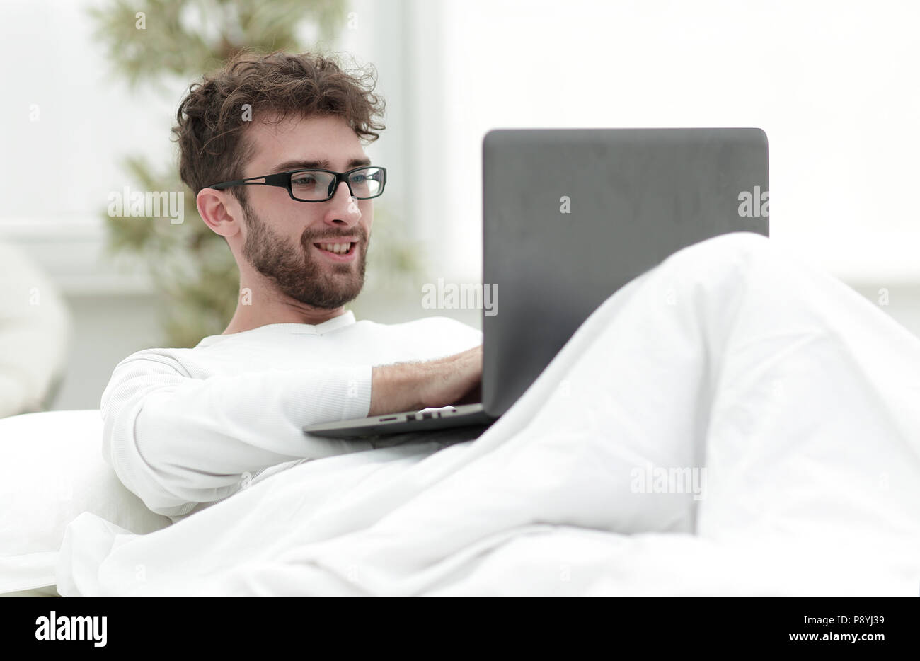 handsome man working on laptop lying on bed Stock Photo - Alamy