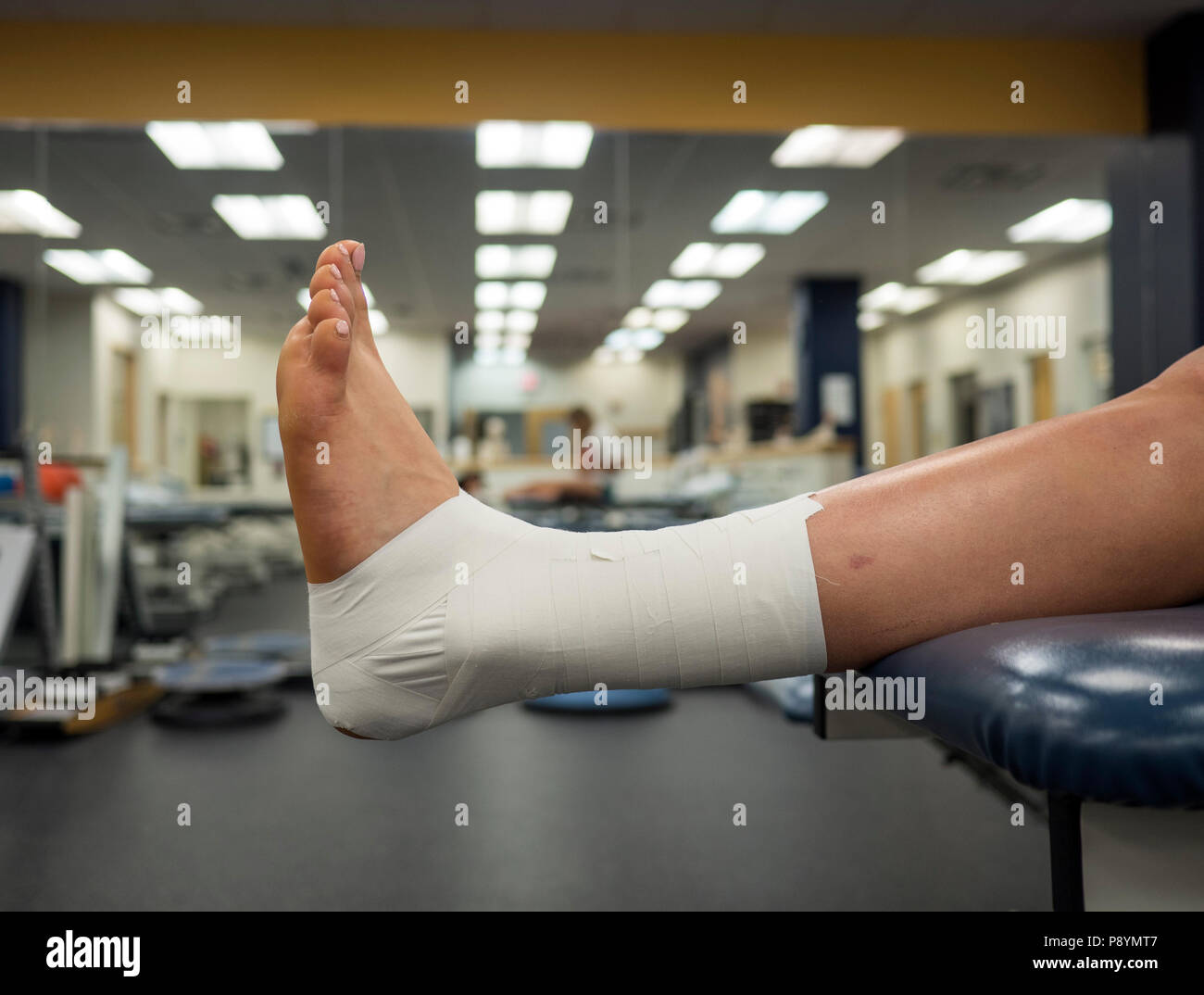 Athlete's foot with an ankle tape job for support hanging off a table ...