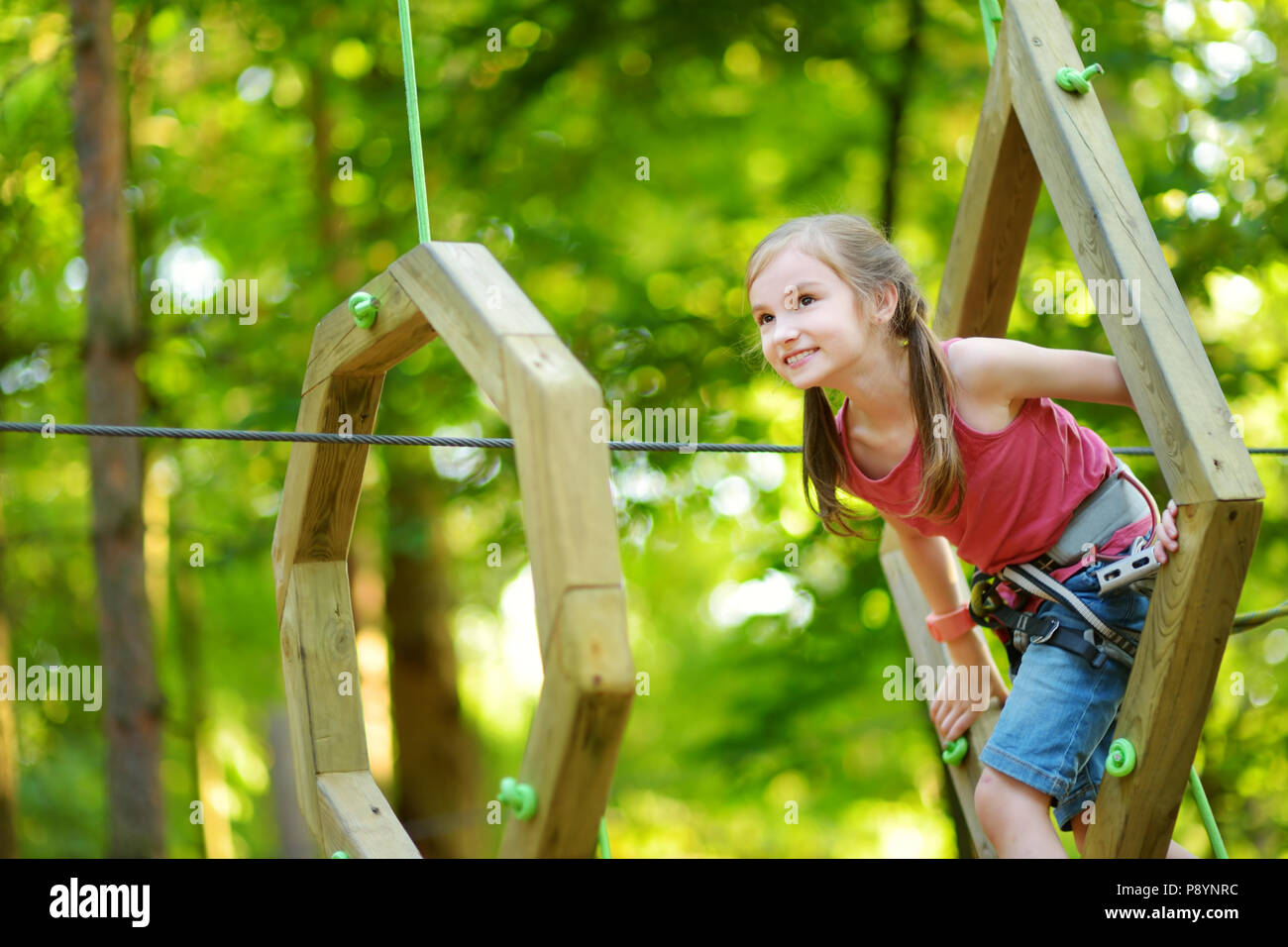 Adorable little girl enjoying her time in climbing adventure park on ...