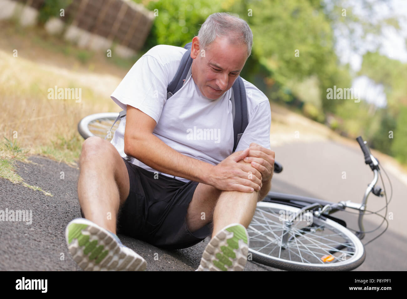 cyclist fell down from bike with injured knee joint Stock Photo - Alamy