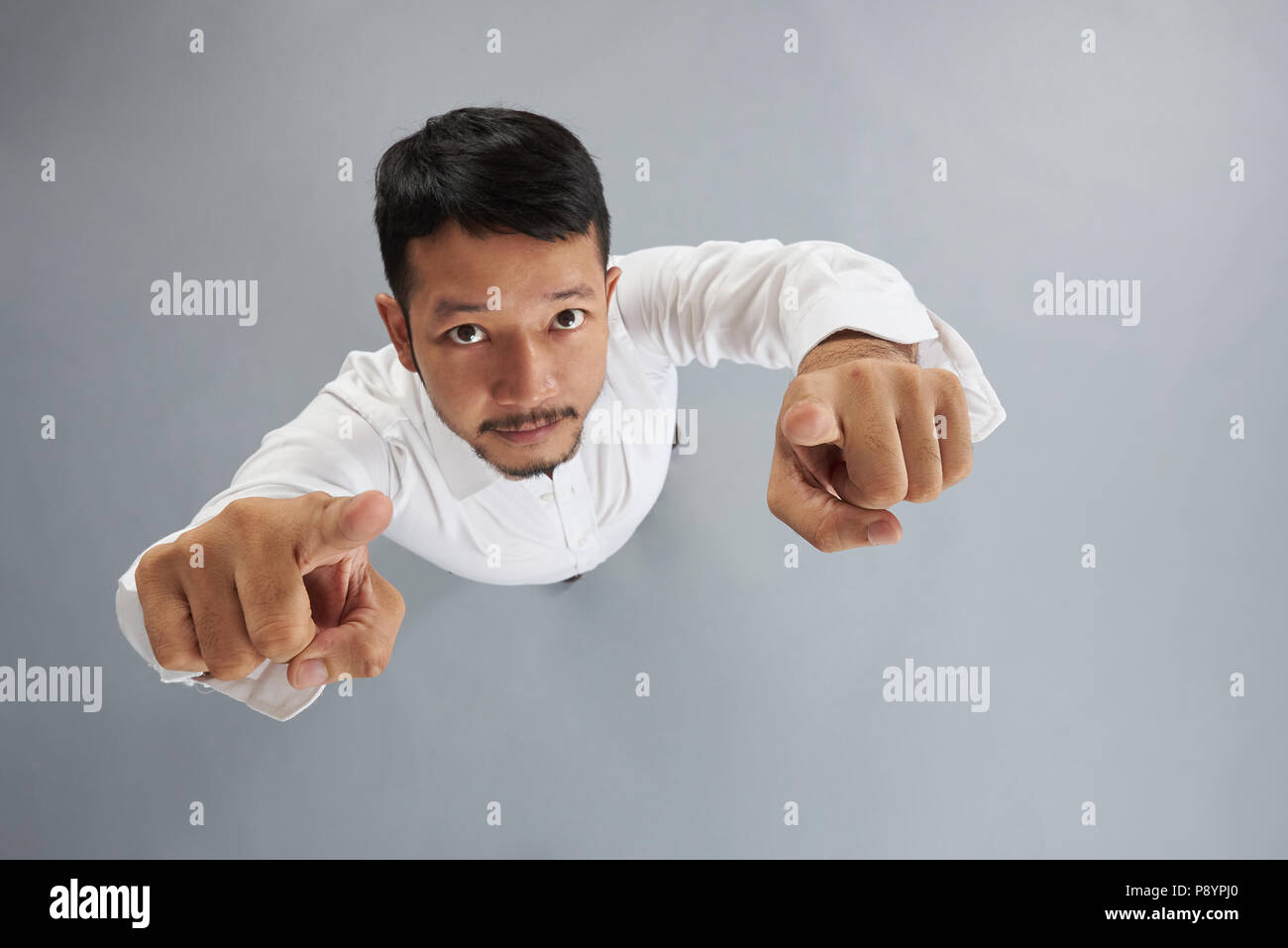 Asian man point fingers into camera above top view isolated on gray ...