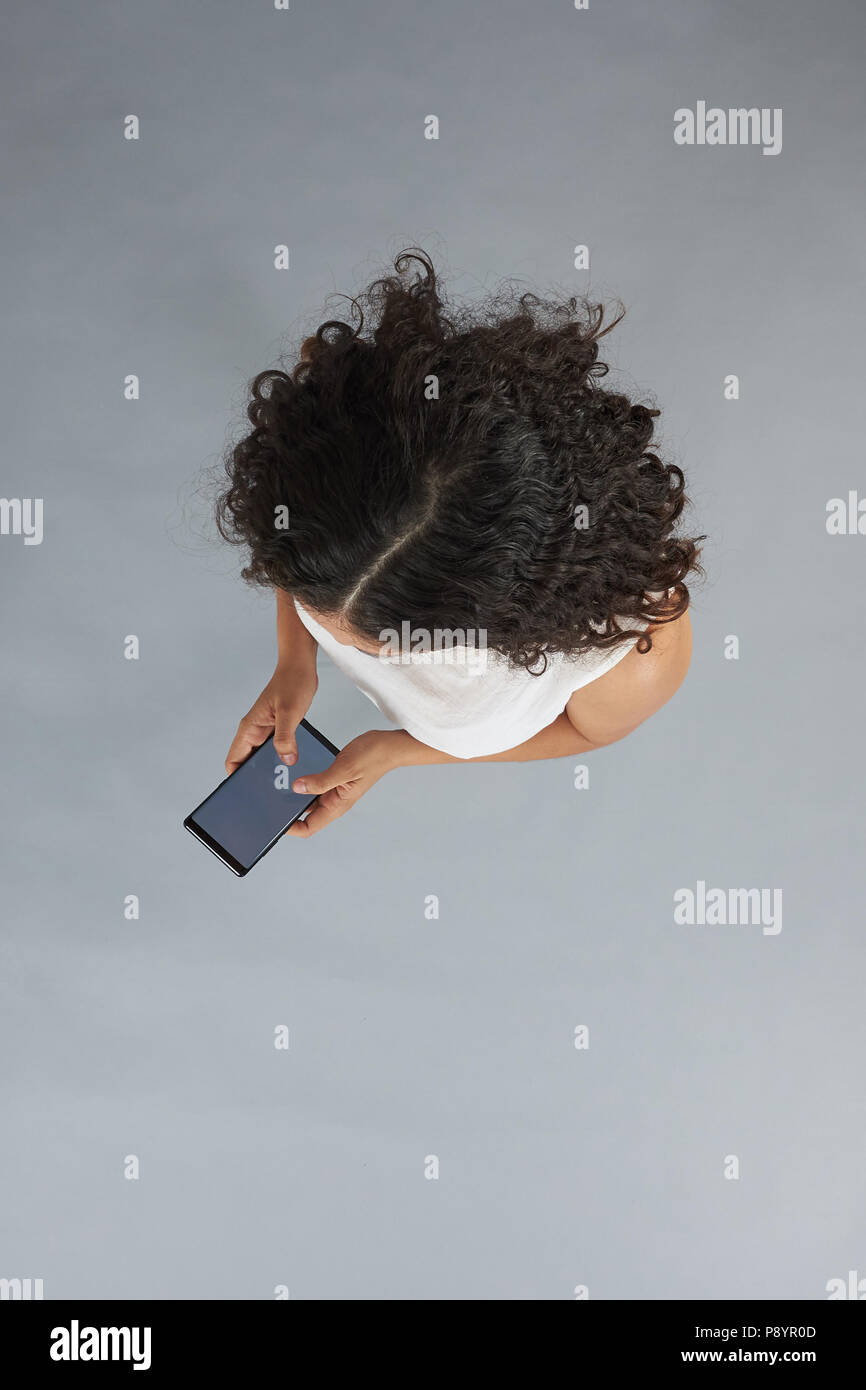 Woman with dark curly hair using smartphone above top view isolated on ...