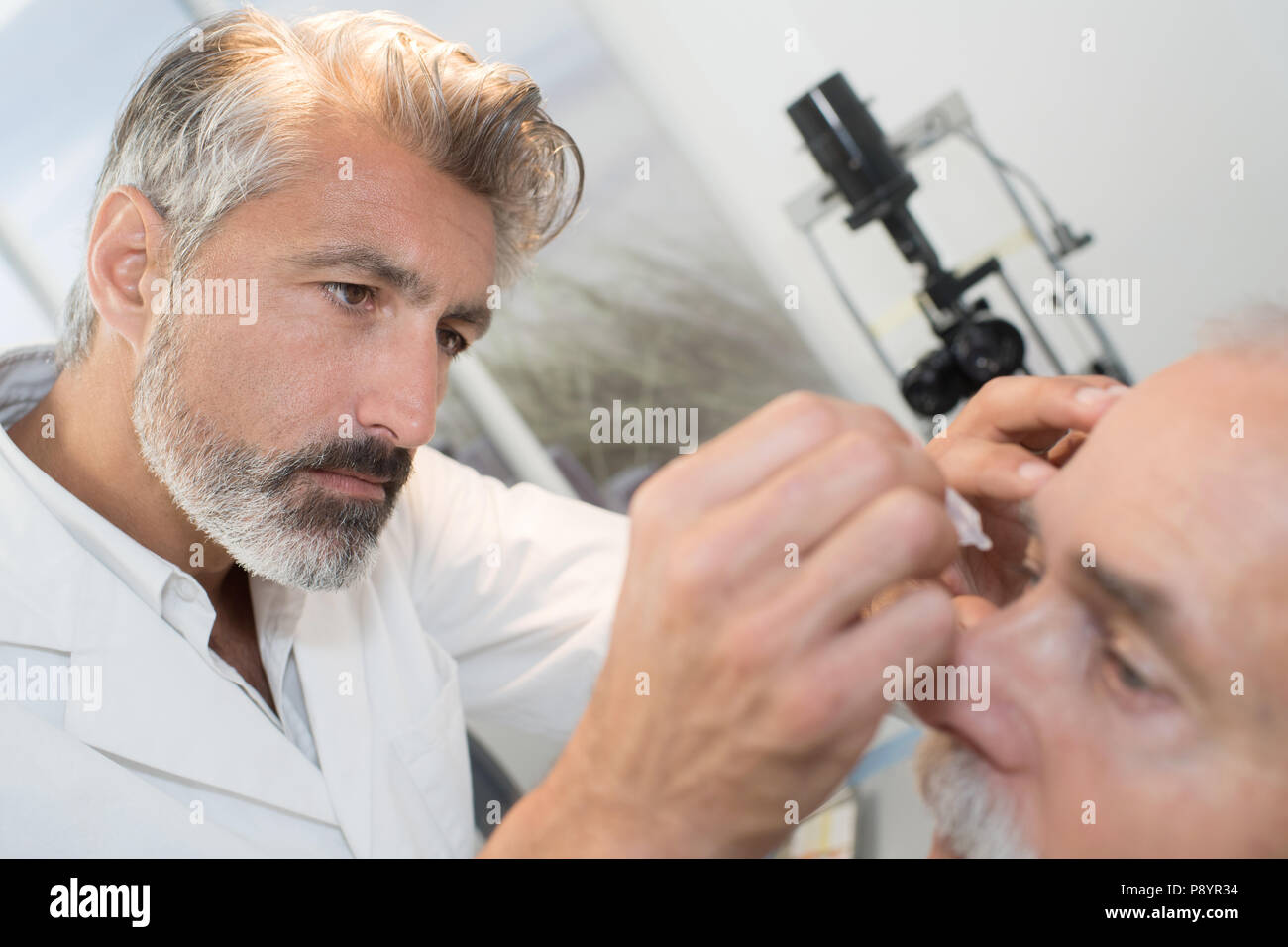 doctor dripping eye drops to patient Stock Photo - Alamy