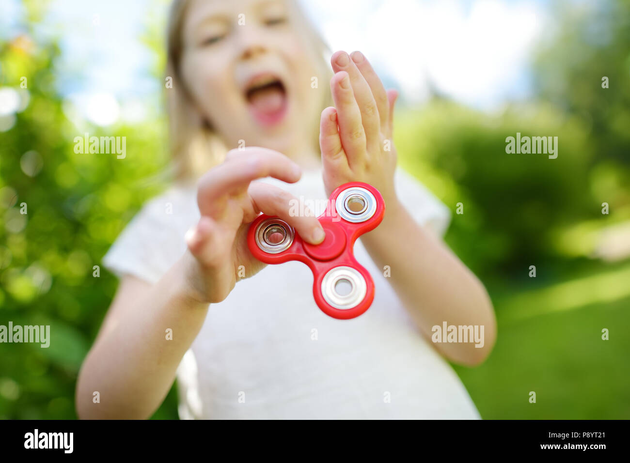 Cute school girl playing with colorful fidget spinner on the playground ...