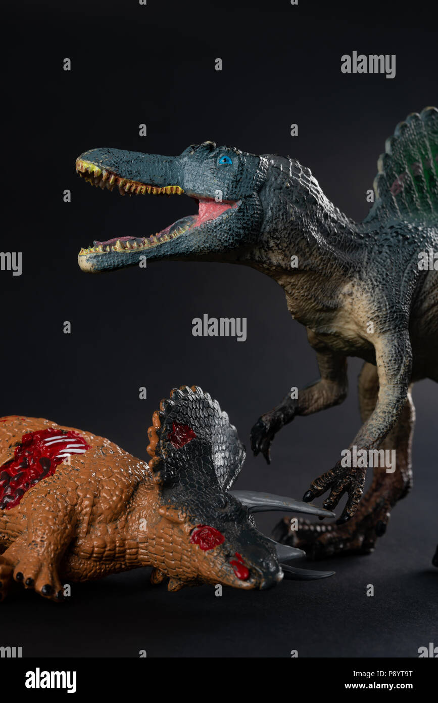 spinosaurus with a triceratops body nearby on dark background vertical ...