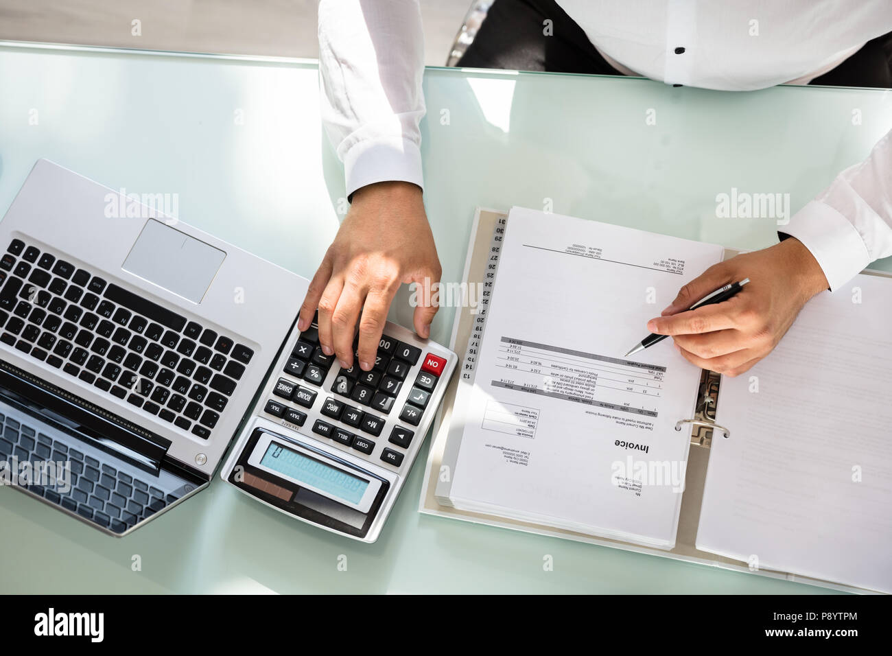 High angle view of a businessman's hand calculating bill in office ...
