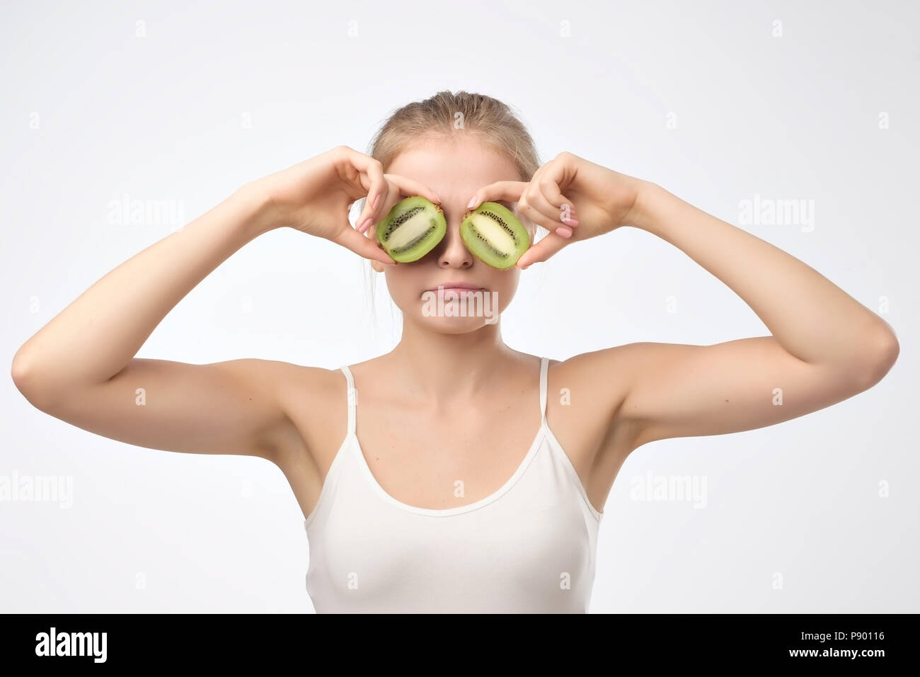 Kiwi. Healthy fruit funny woman holding kiwi fruit for her eyes. Sad ...