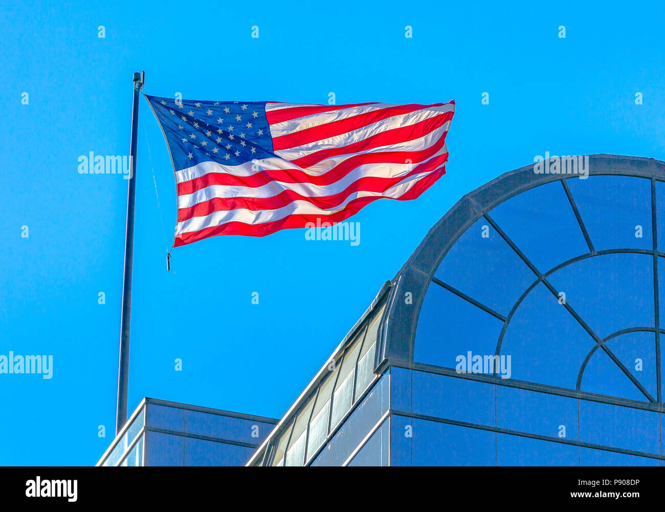 American flag blowing in the wind on building Stock Photo - Alamy
