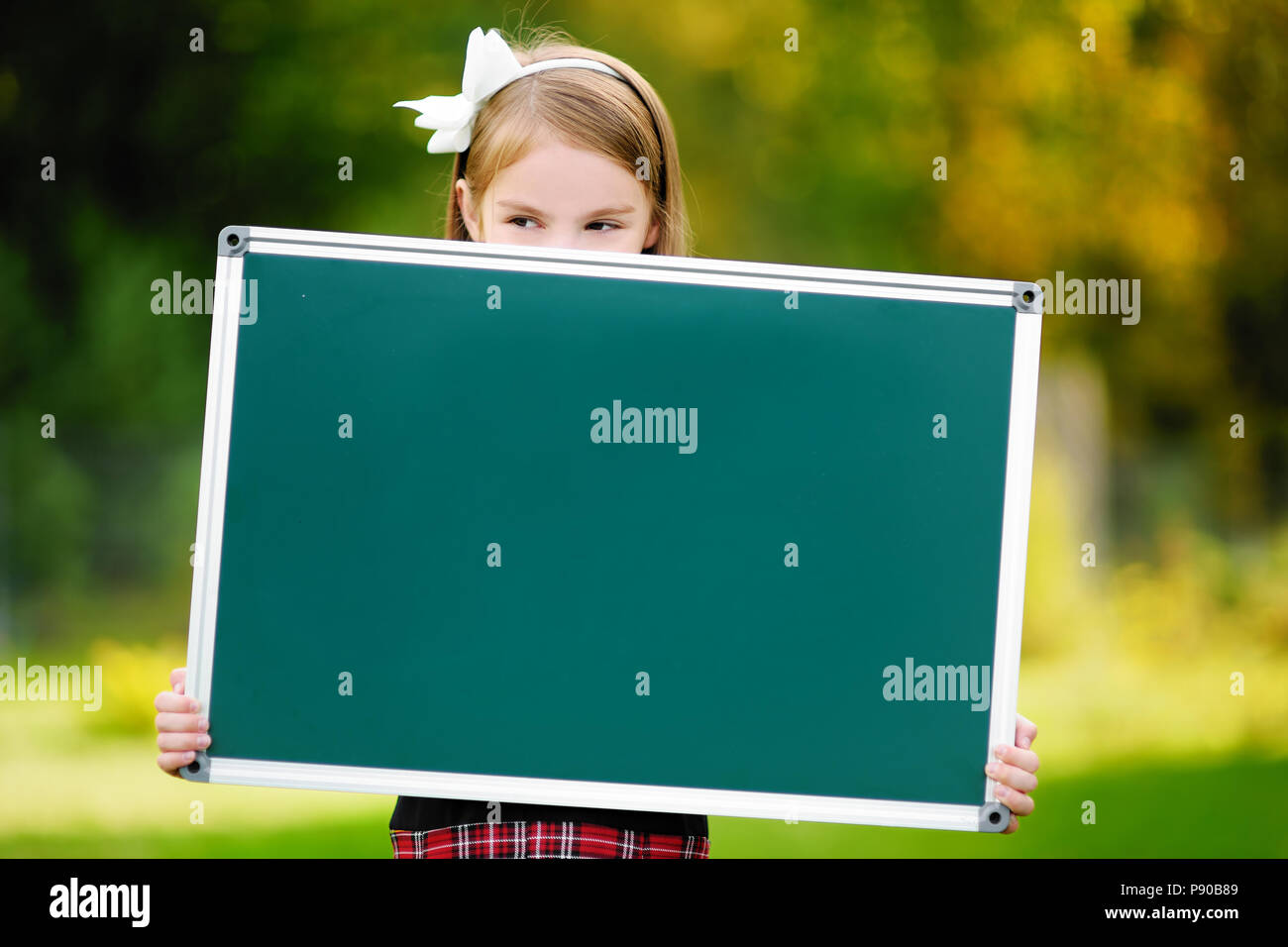 Adorable little schoolgirl holding blank chalkboard Stock Photo - Alamy