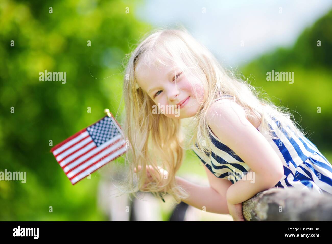 Adorable little girl holding american flag outdoors on beautiful summer ...