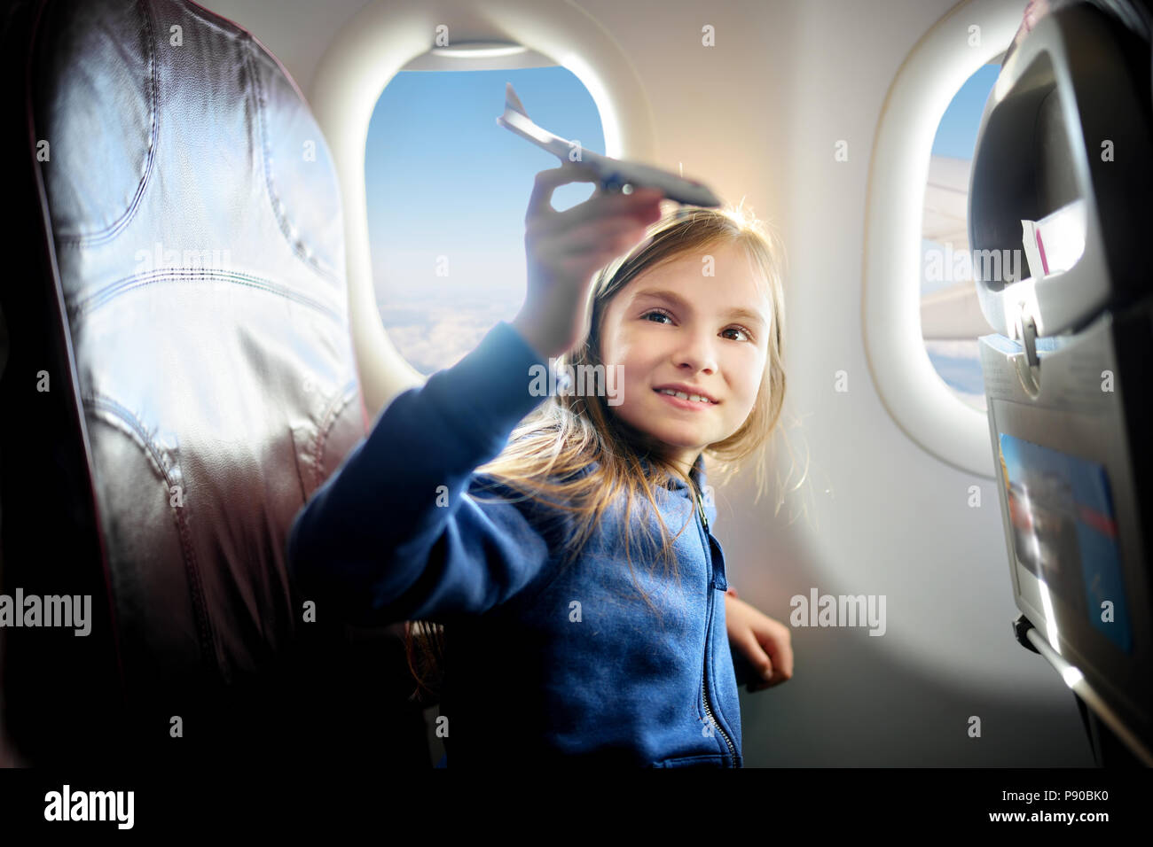 Adorable little girl traveling by an airplane. Child sitting by ...