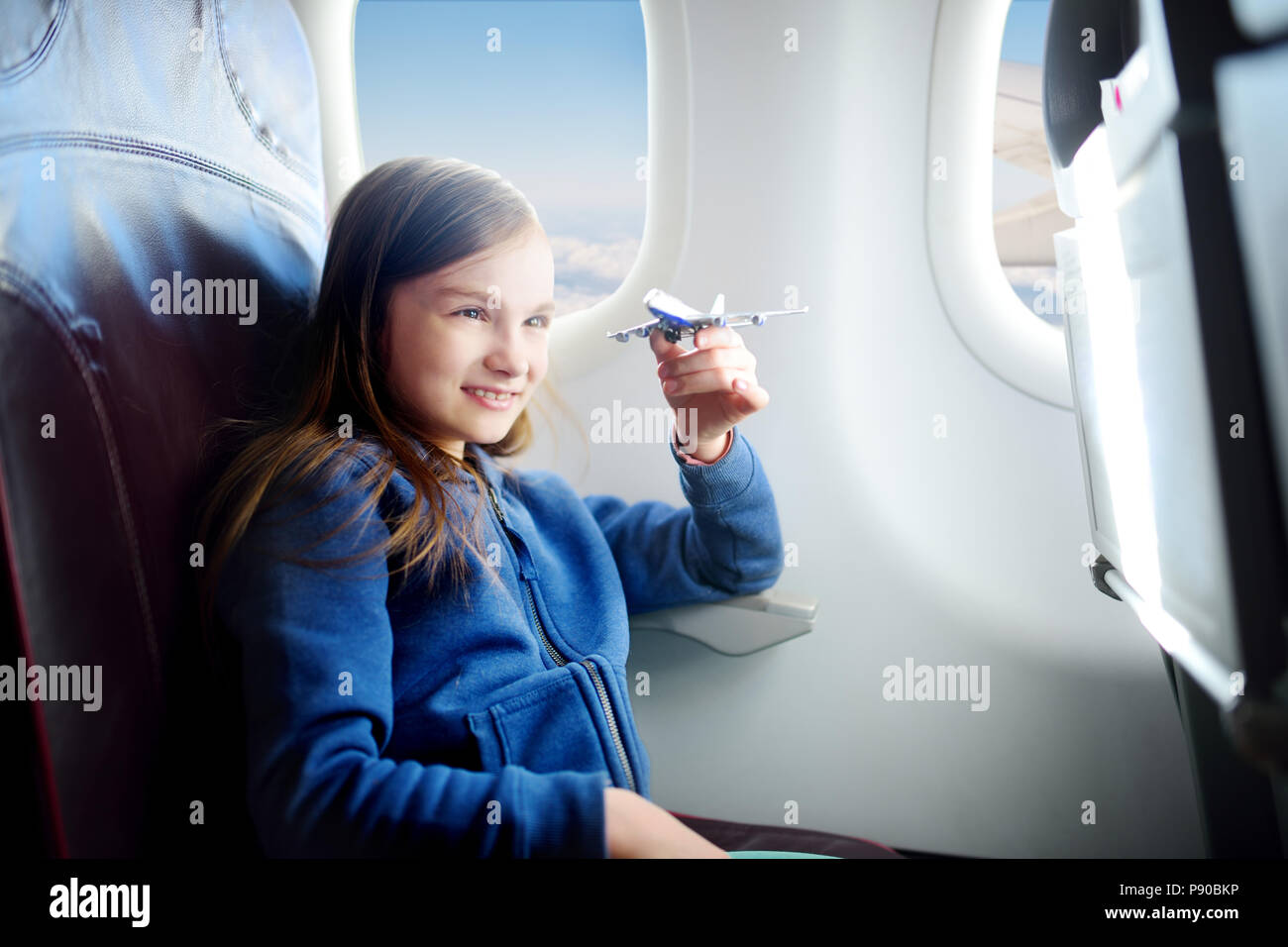 Adorable little girl traveling by an airplane. Child sitting by ...