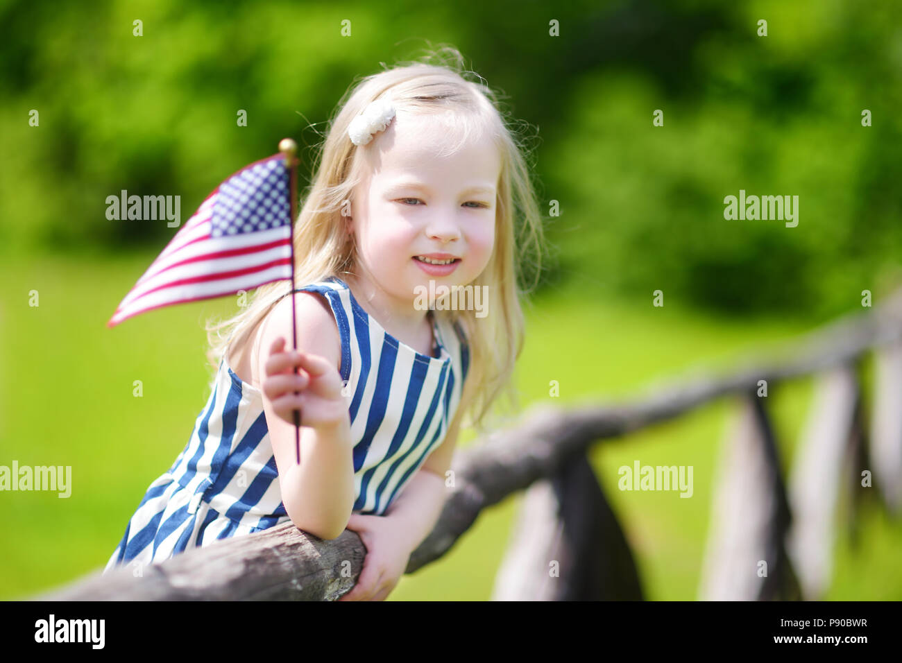 Adorable little girl holding american flag outdoors on beautiful summer ...