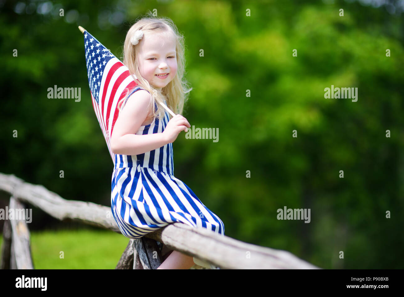 Adorable little girl holding american flag outdoors on beautiful summer ...