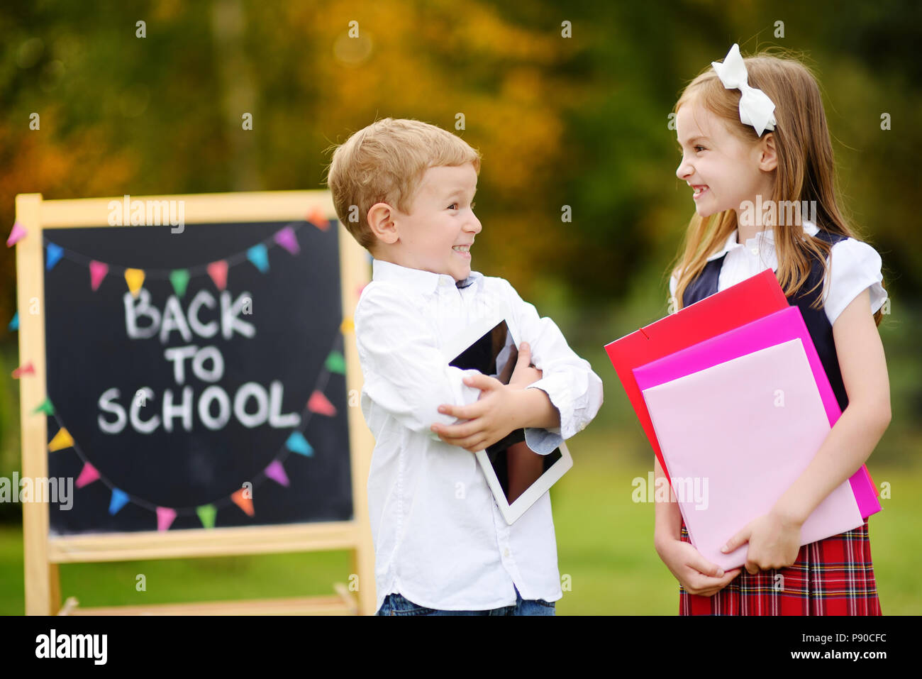 Two adorable little schoolkids feeling very excited about going back to ...