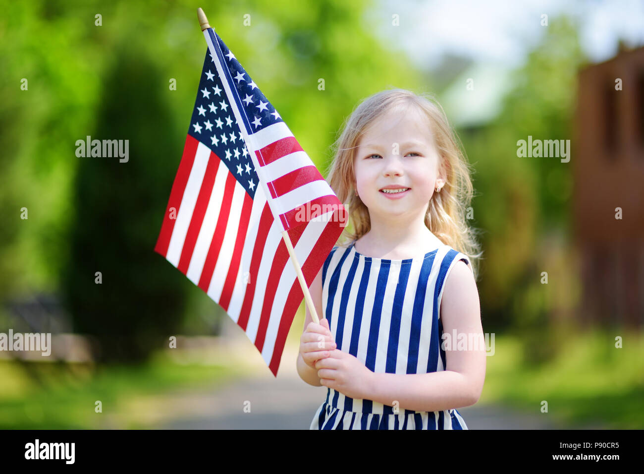Adorable little girl holding american flag outdoors on beautiful summer ...