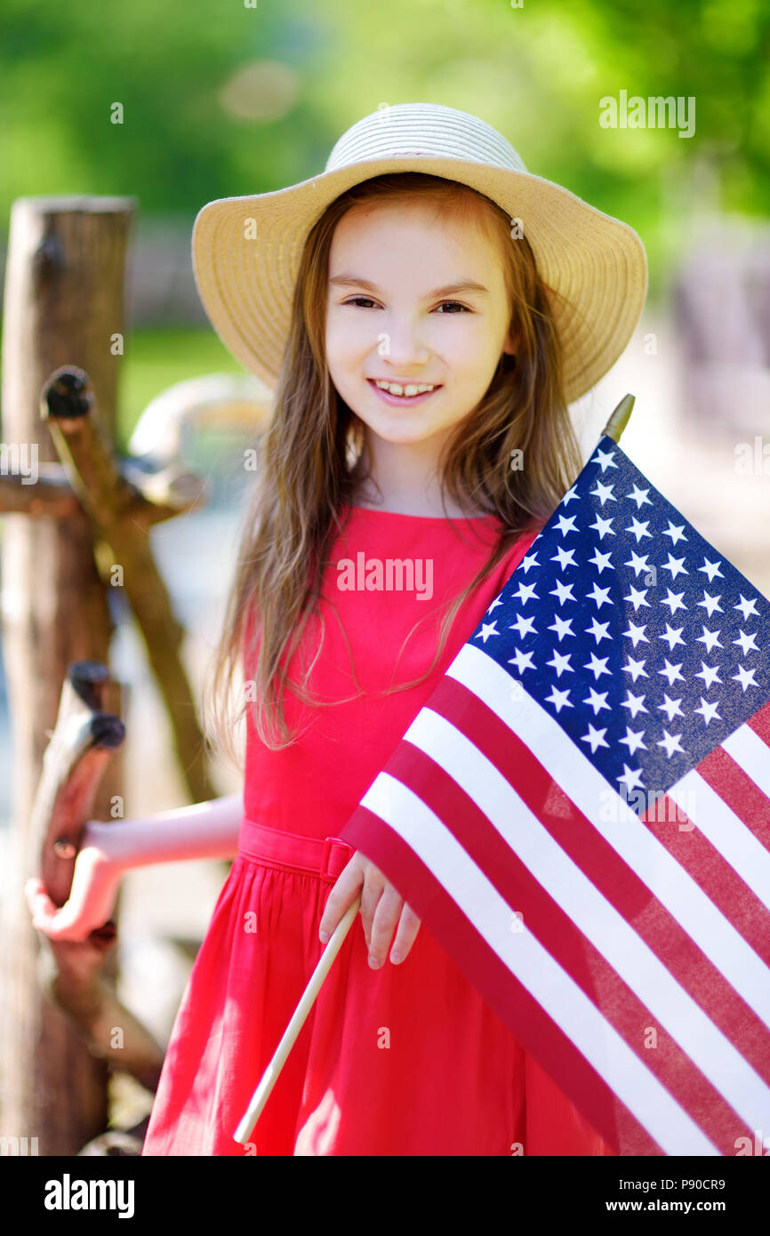 Adorable little girl holding american flag outdoors on beautiful summer ...