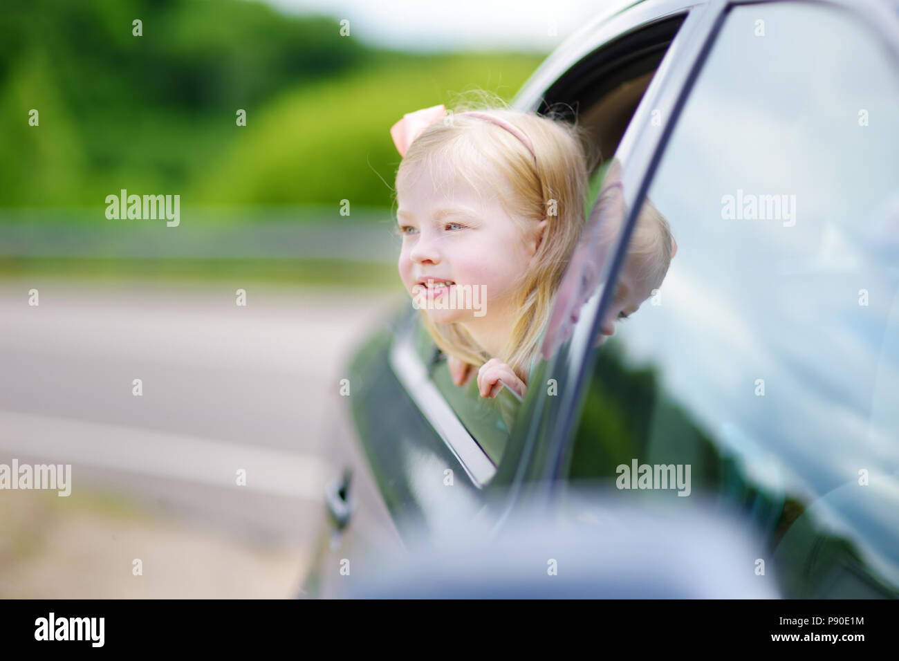 Funny little girl is sticking her head out the car window looking ...