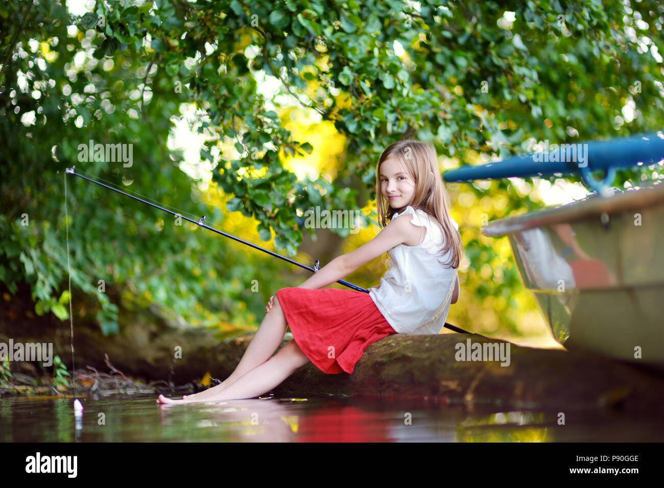 Cute little girl fishing with a fishing rod by a river on warm and ...