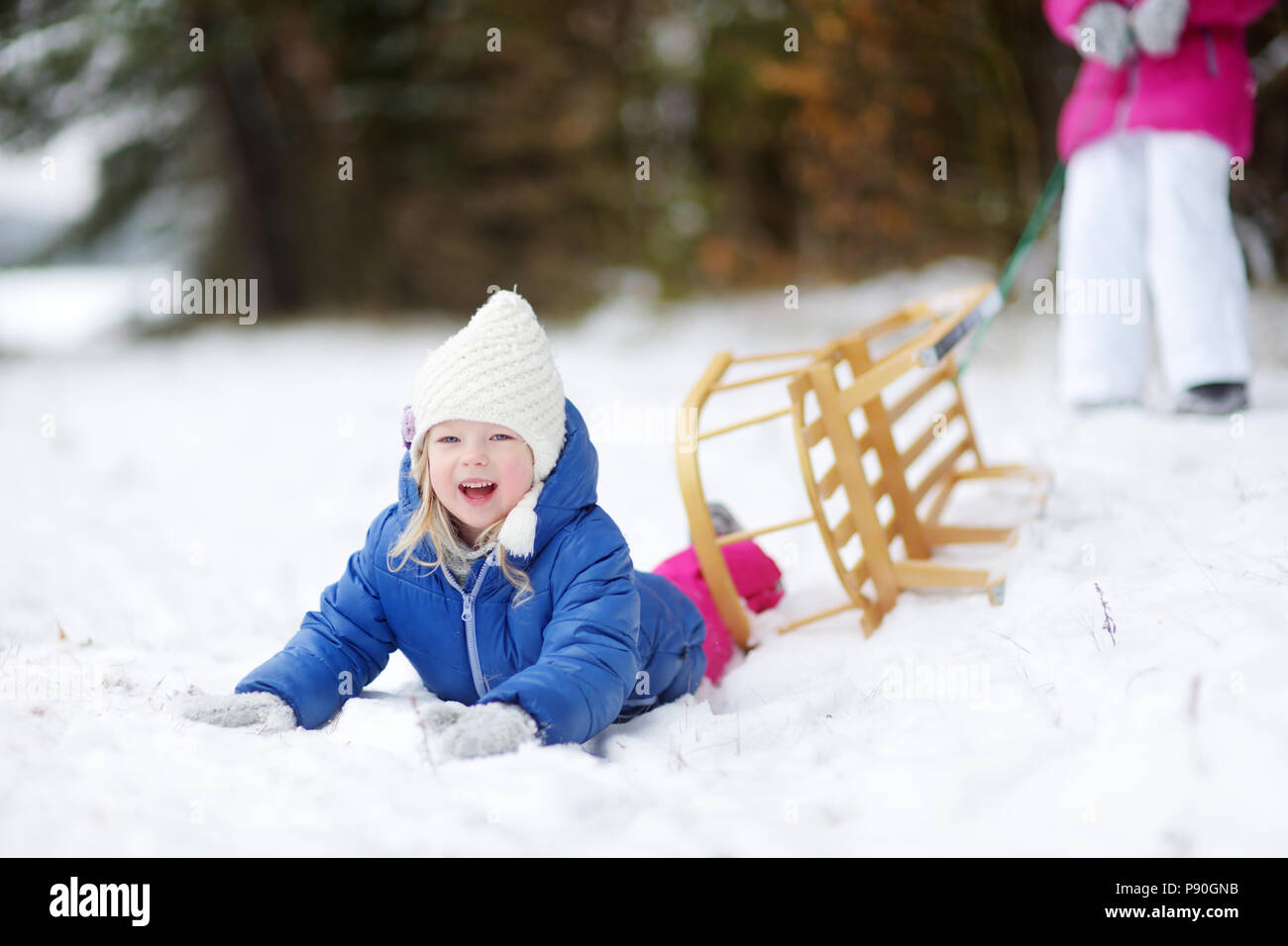 Two adorable little sisters enjoying sleight ride on snowy winter day ...