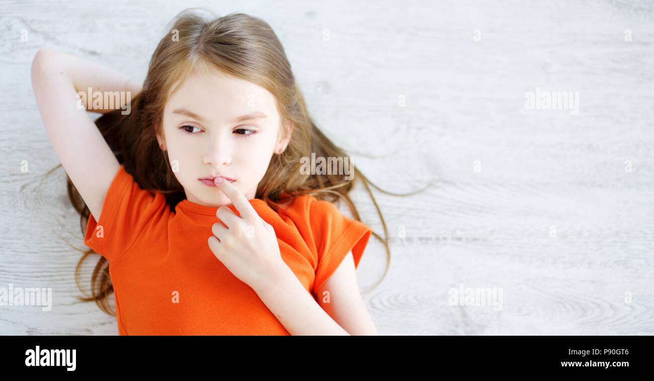 Funny little girl lying on white wooden floor Stock Photo - Alamy