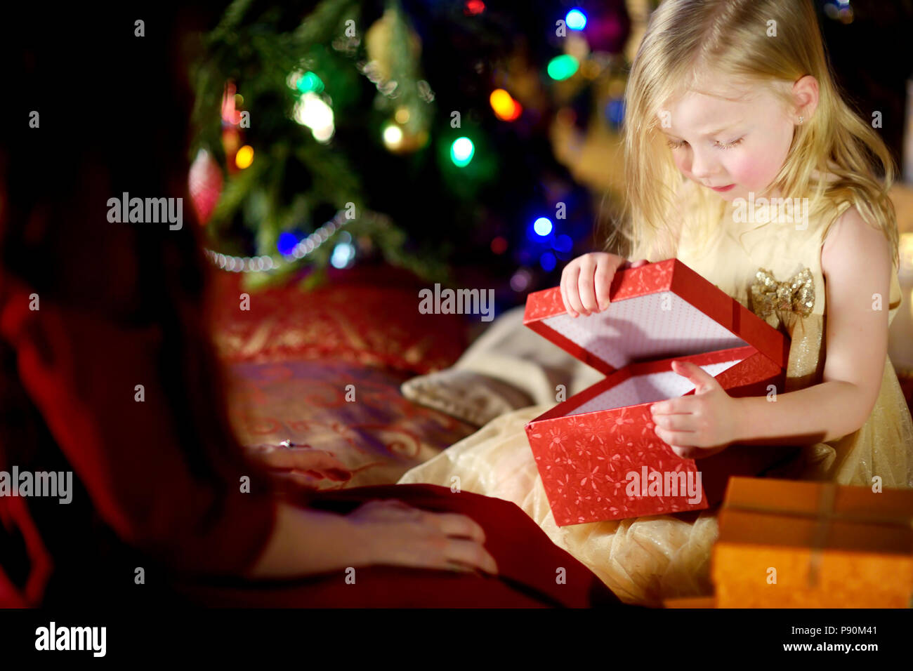 Happy little girl getting a Christmas gift from her parent by a ...