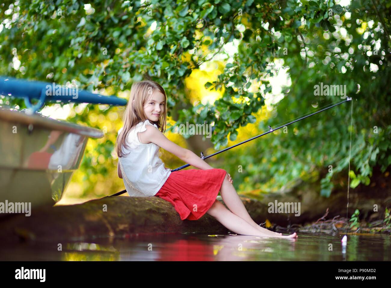 Cute little girl fishing with a fishing rod by a river on warm and ...