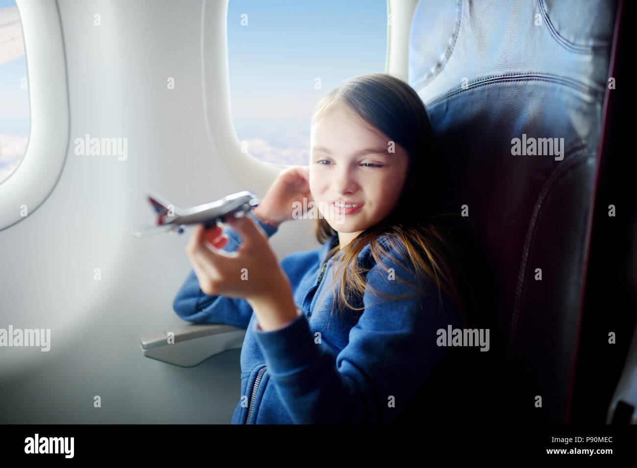 Adorable little girl traveling by an airplane. Child sitting by ...