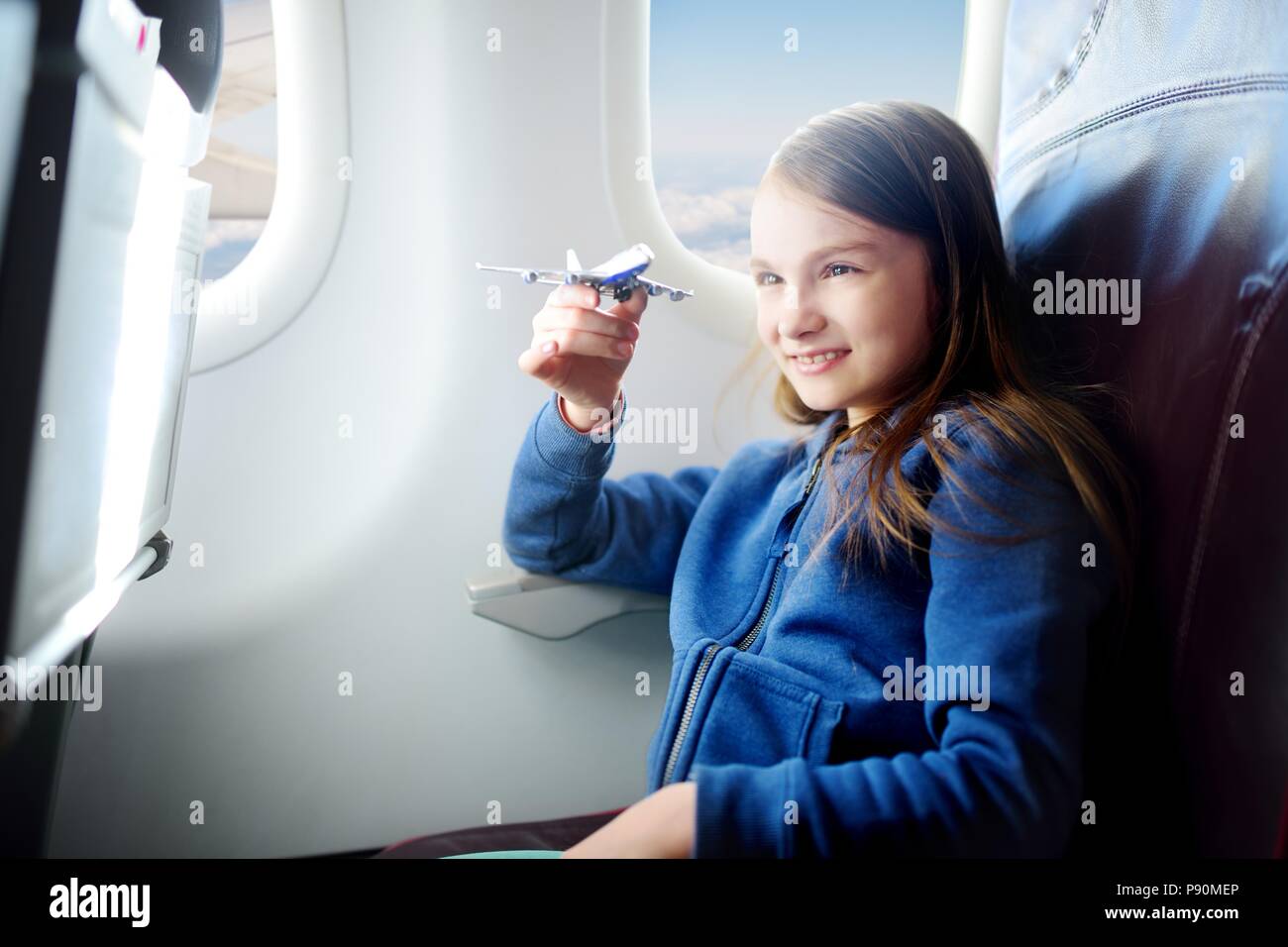 Adorable little girl traveling by an airplane. Child sitting by ...