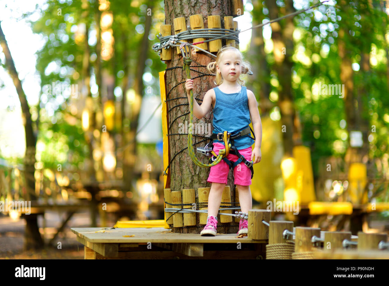 Adorable little girl enjoying her time in climbing adventure park on ...