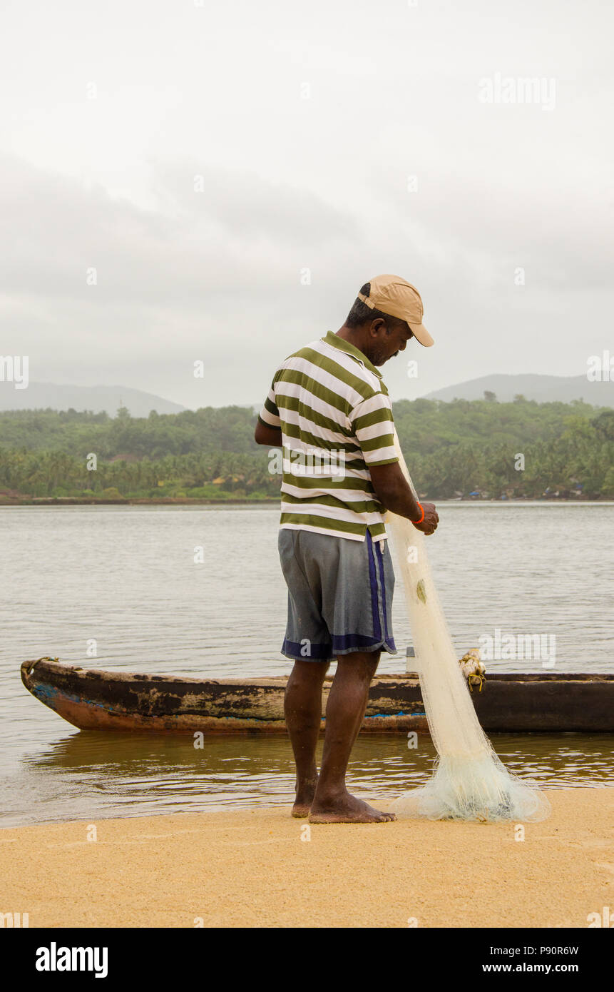 Fisherman folding fishing net at the end of day on Betul beach ...