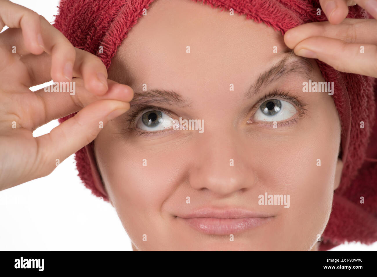Young beautiful girl pulls out her eyebrows with tweezers metal on a ...