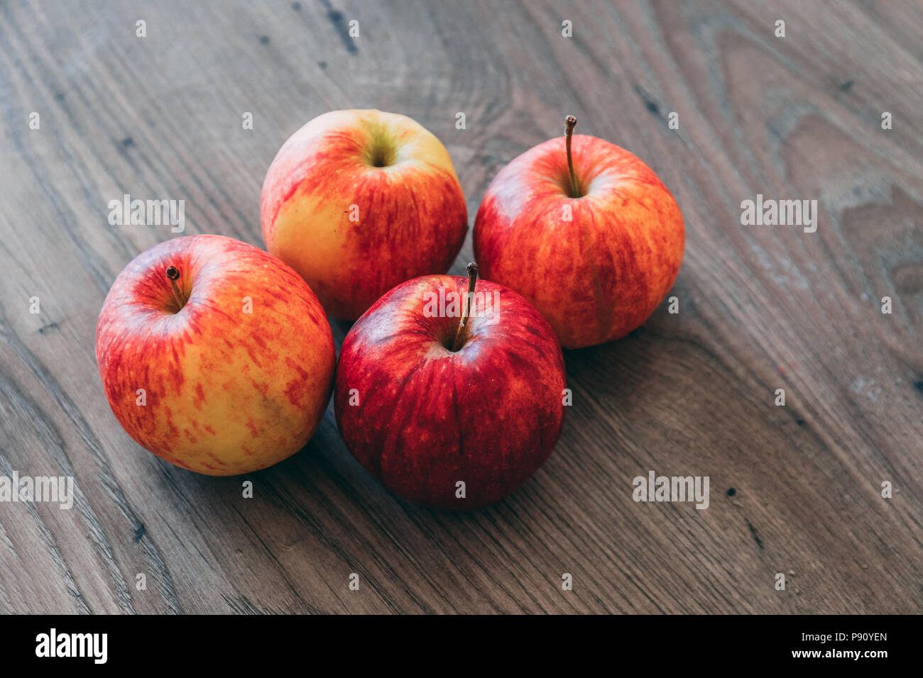 A bunch of apples lay on top of a dark wood table Stock Photo - Alamy