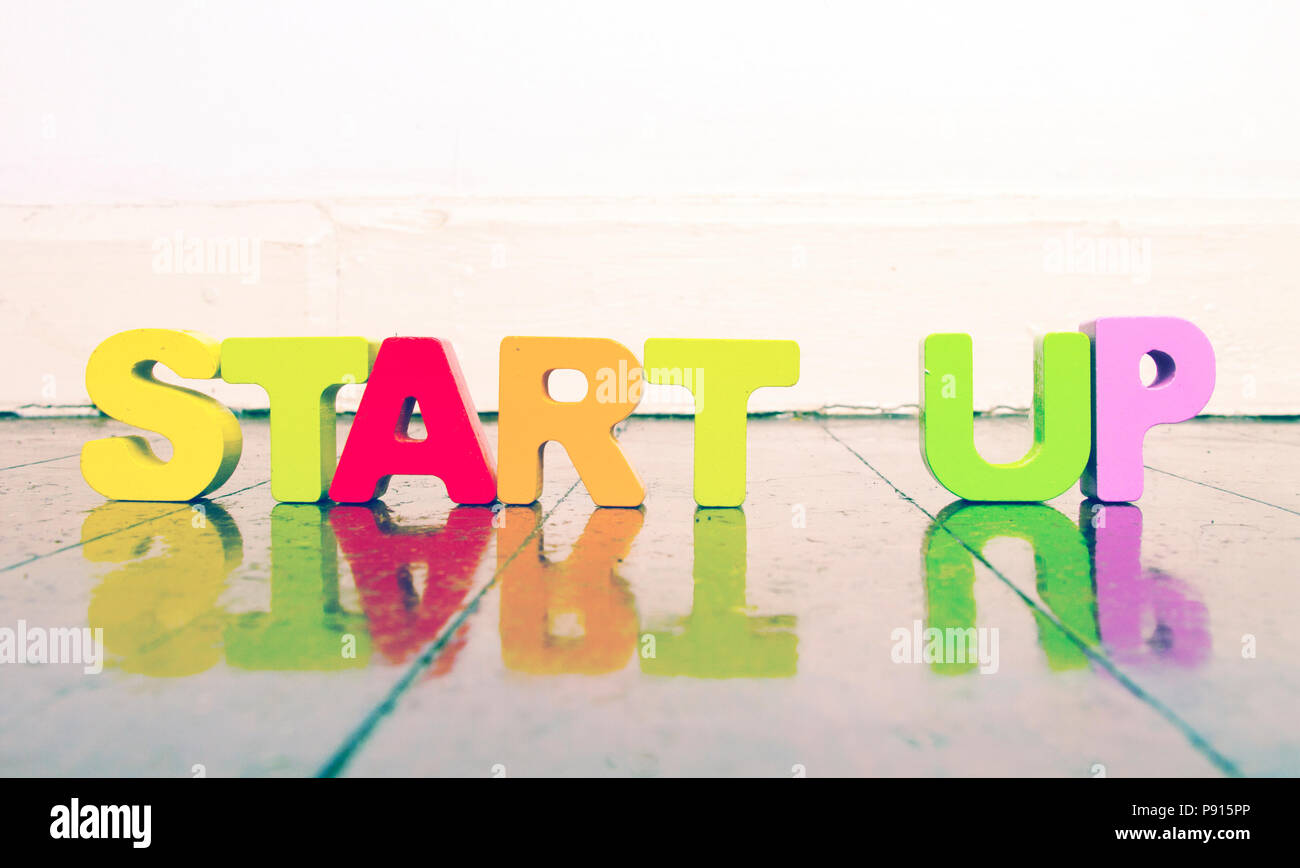 the word START UP with wooden letters on a wooden floor with reflection ...
