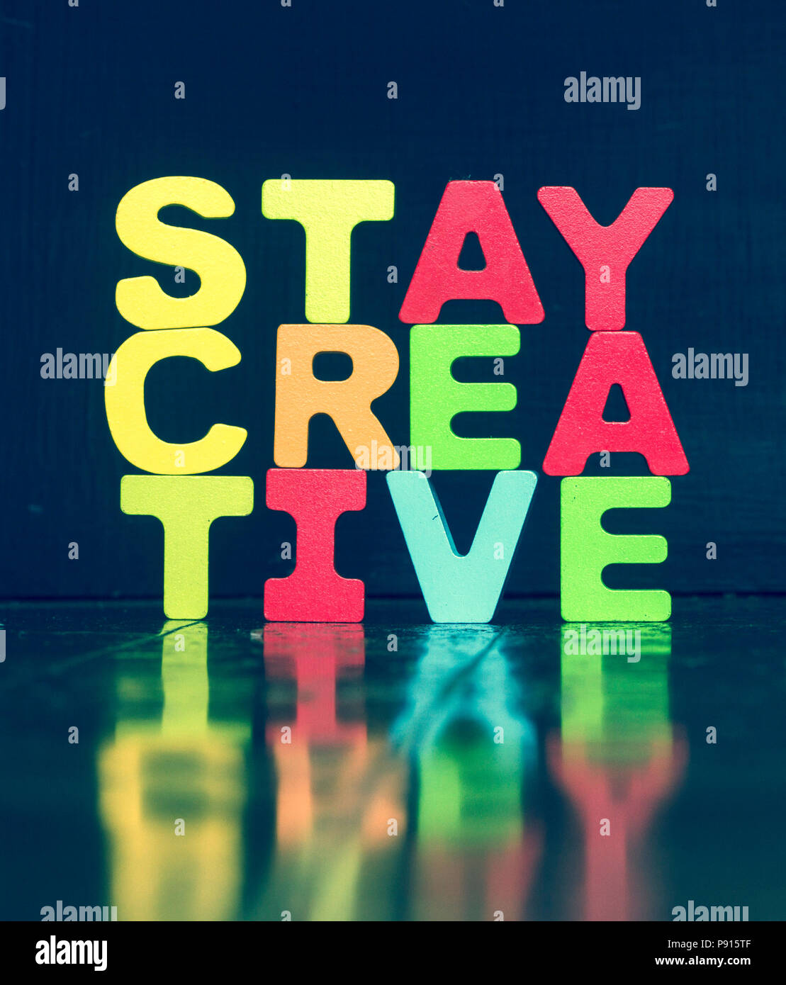 the word STAY CREATIVE with a black background on a floor with ...
