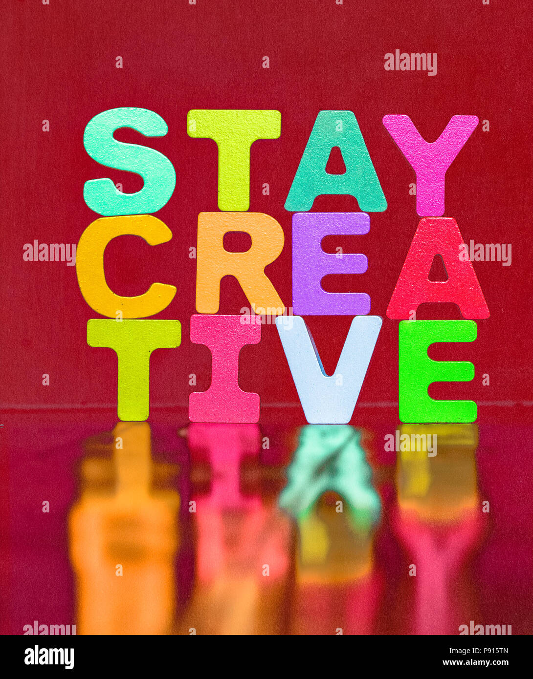 the word STAY CREATIVE on a red felt background on a floor with ...