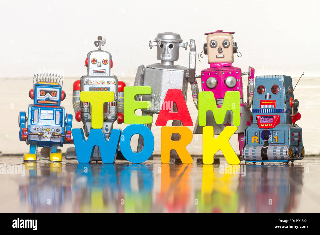 the word TEAM WORK with wooden letters and 5 retro bots on a wooden ...