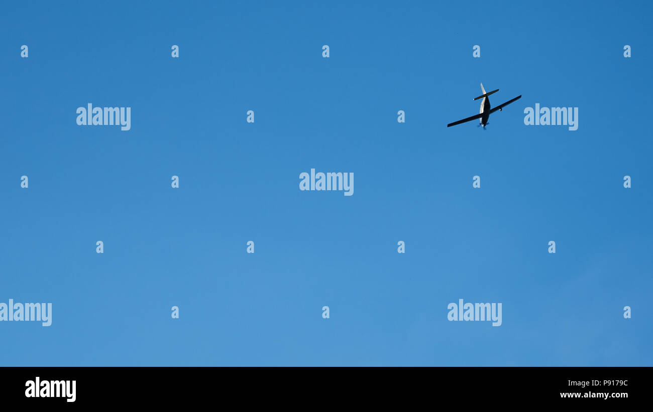 Plane flying through blue sky Stock Photo - Alamy
