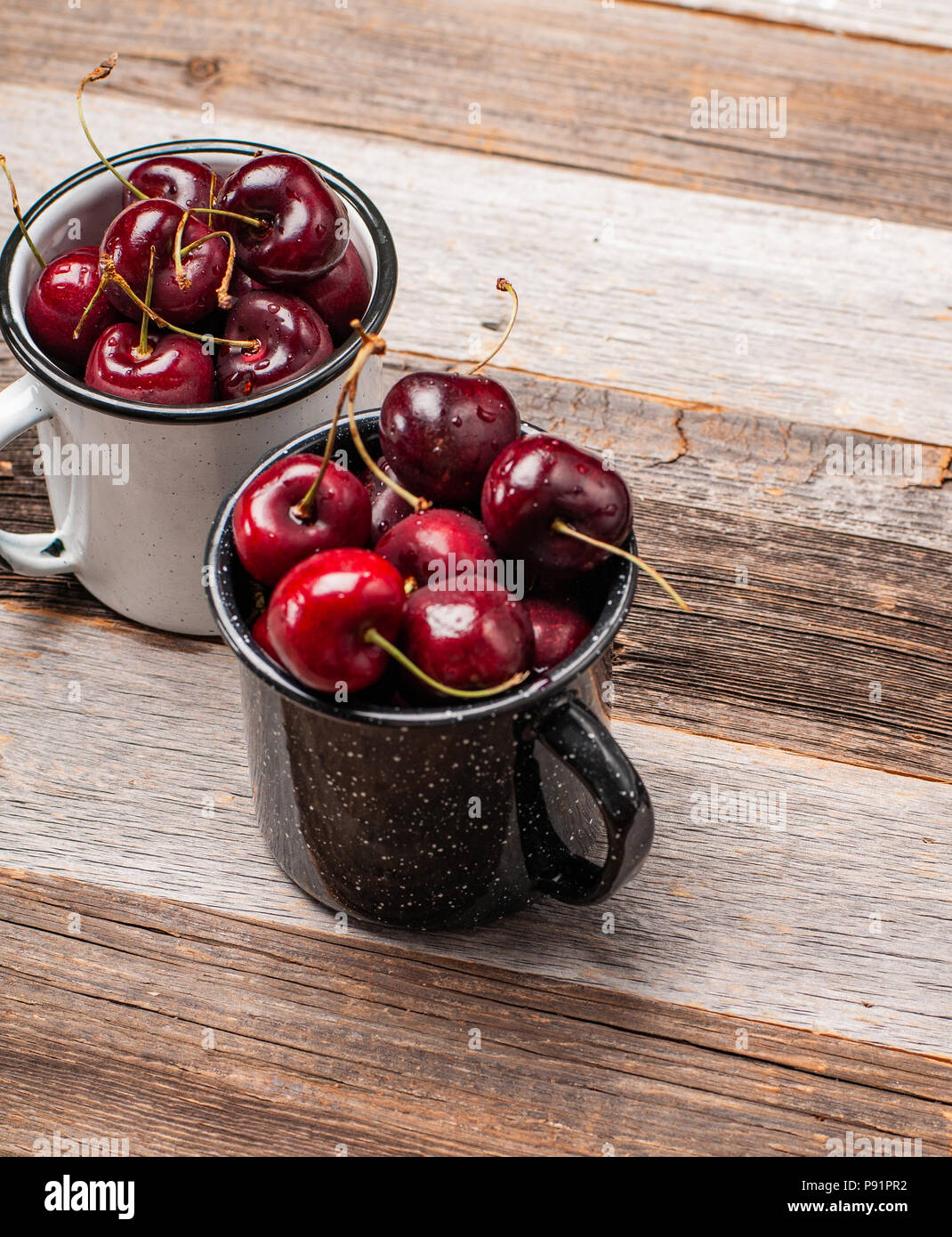 Fresh ripe cherries. Cherries in the enameled cup on wooden table Stock ...