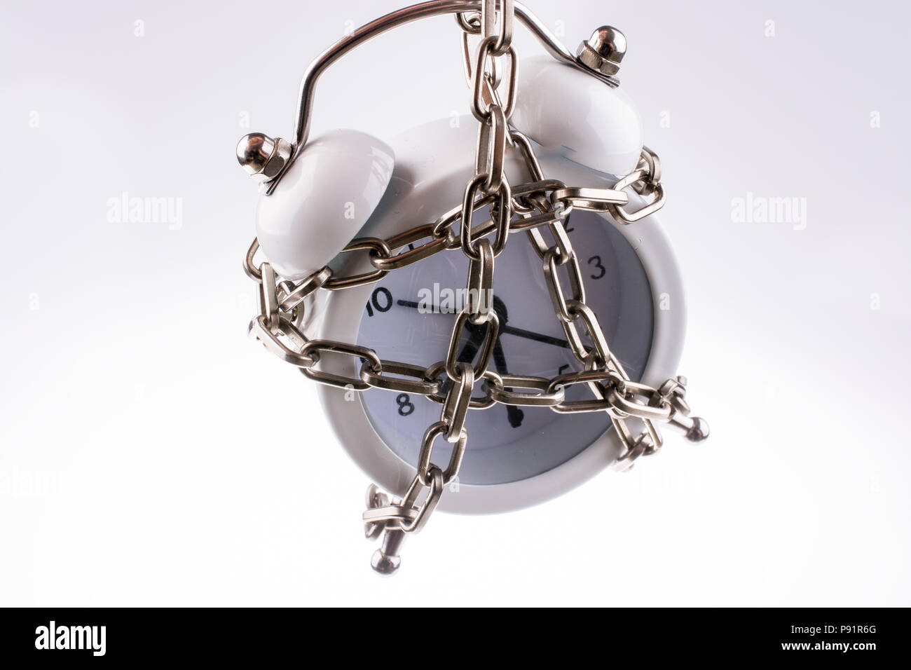 White color alarm clock in chain on a white background Stock Photo - Alamy