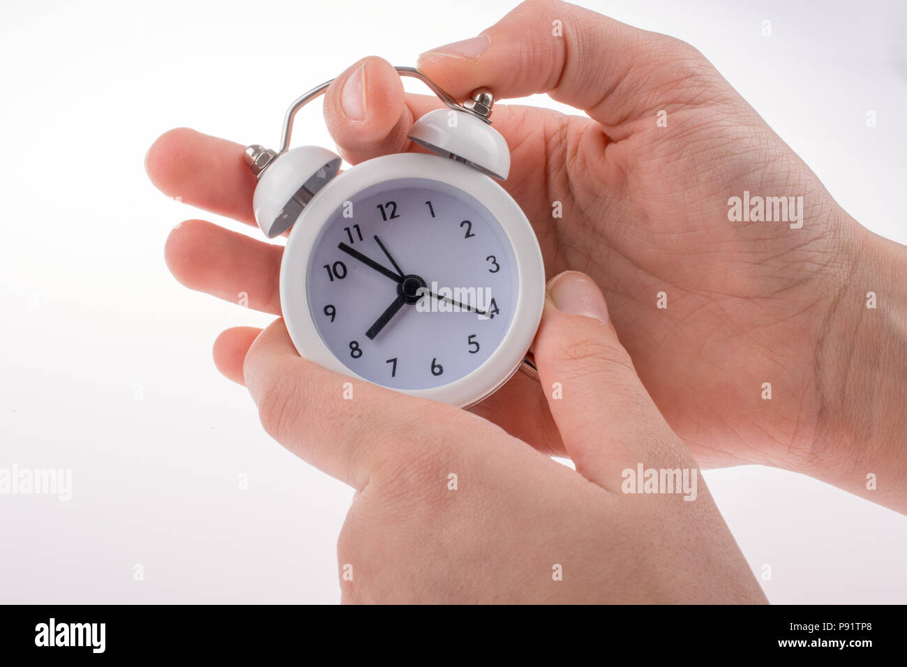 Alarm clock in hand on a white background Stock Photo - Alamy