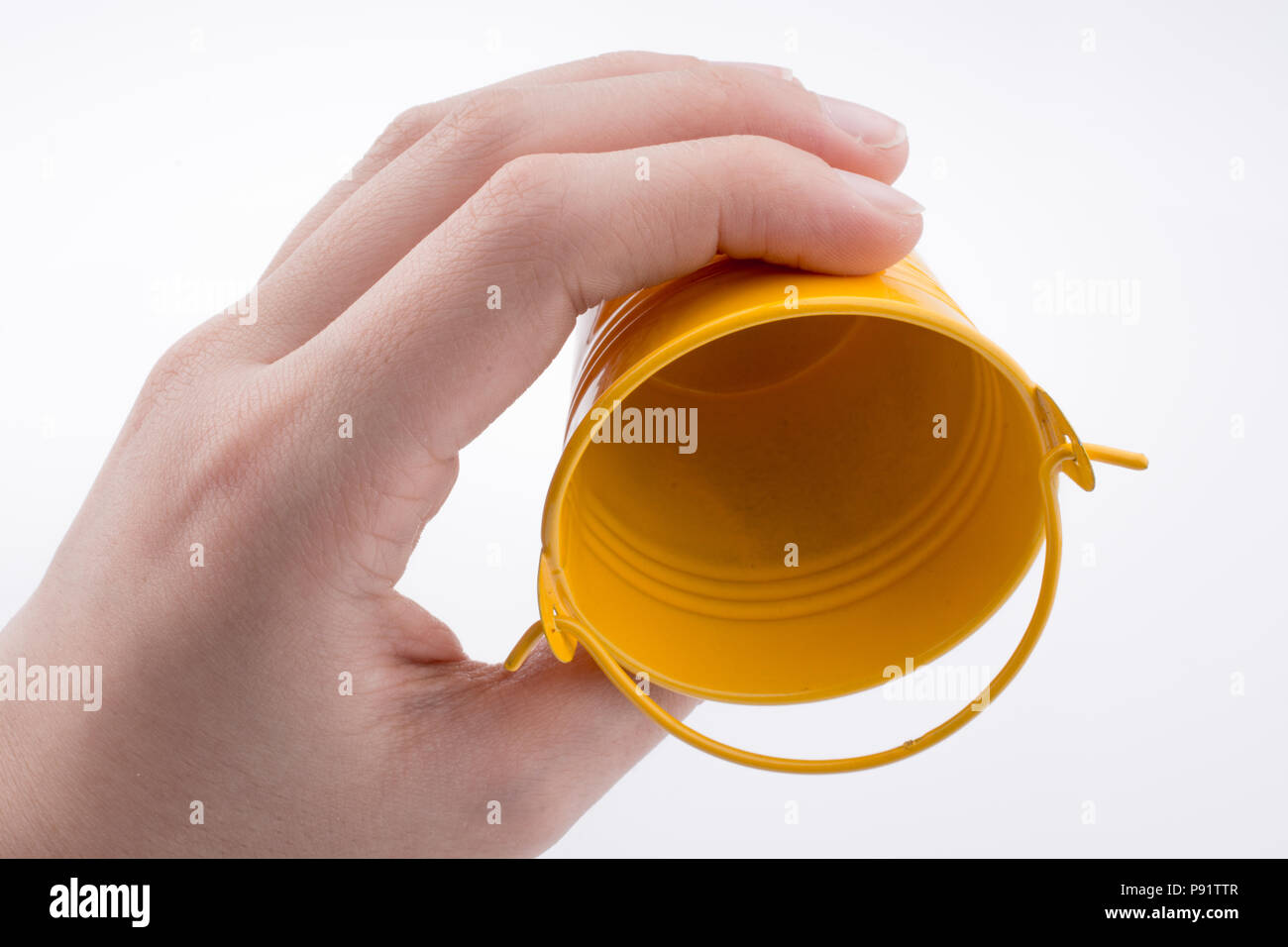 Hand holding a yellow bucket on a white background Stock Photo - Alamy