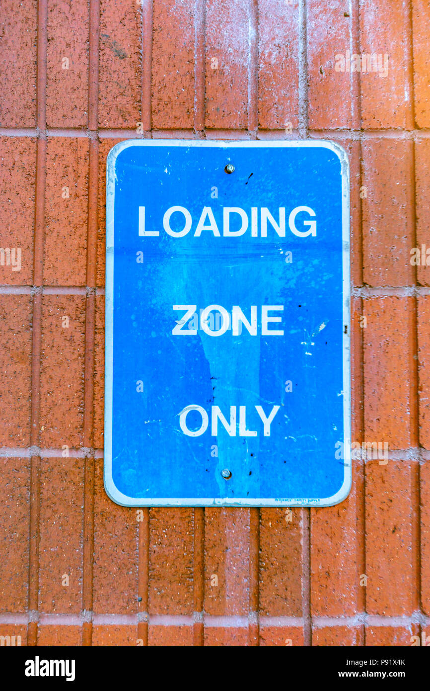 Loading zone only blue sign against brick Stock Photo - Alamy