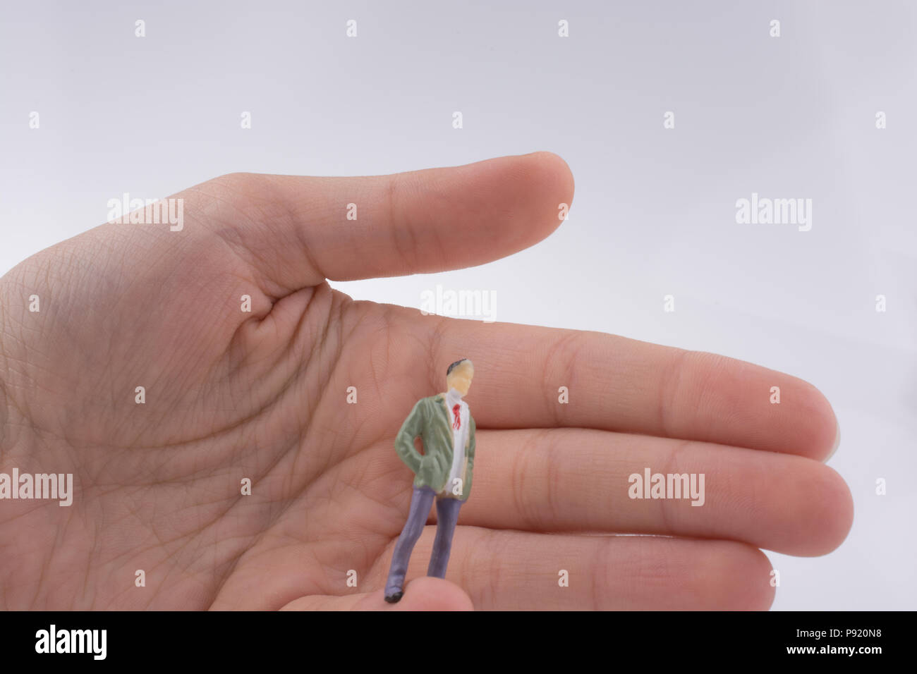 Hand holding a human figure on a white background Stock Photo - Alamy